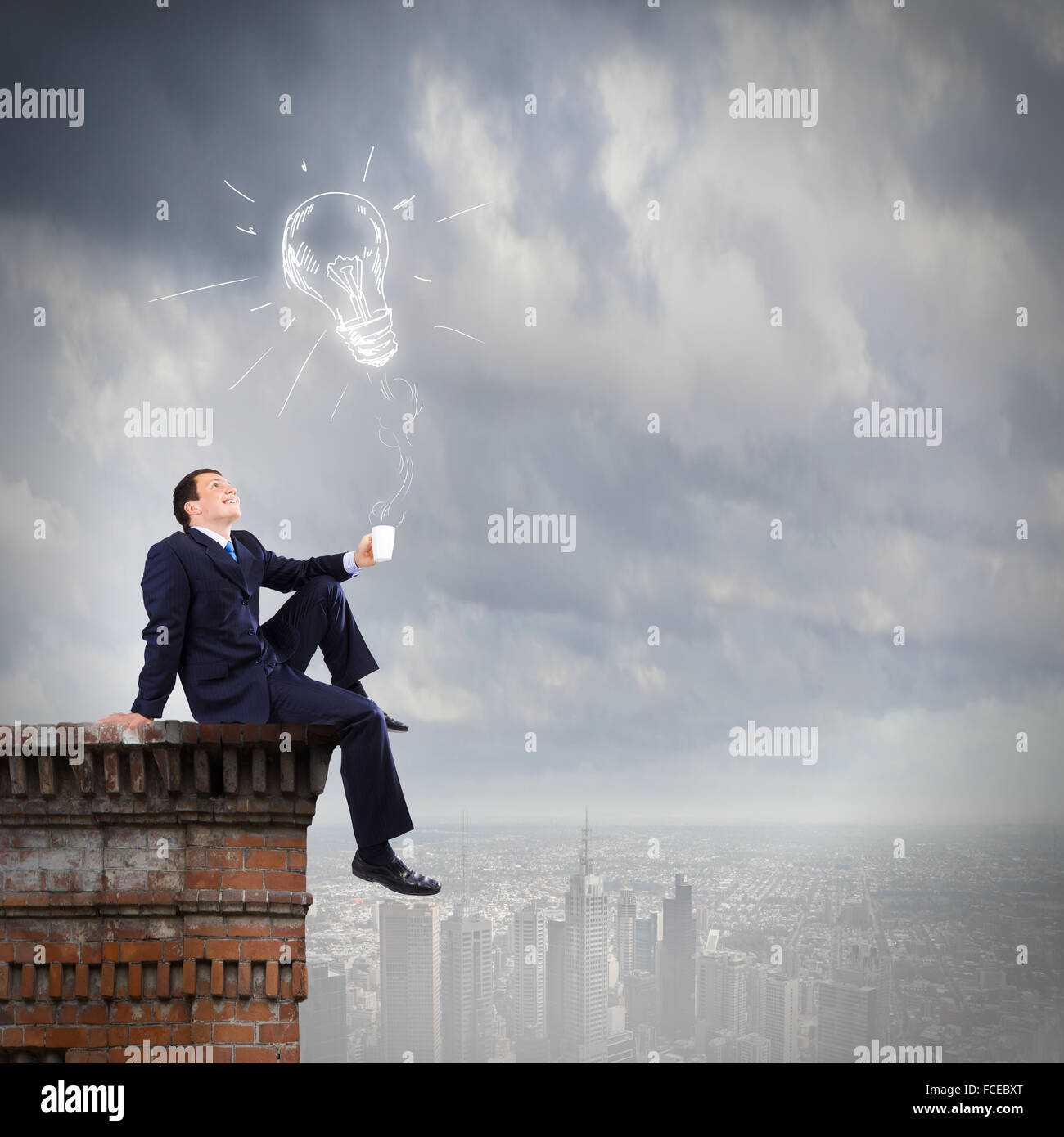 Young businessman sitting on roof of building Stock Photo - Alamy