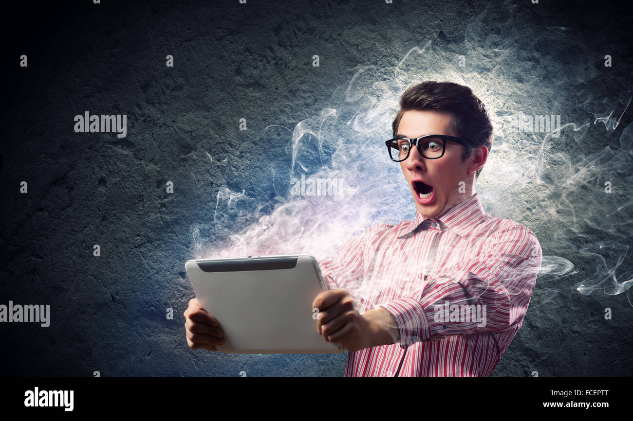 Young man looking shocked in tablet pc Stock Photo - Alamy