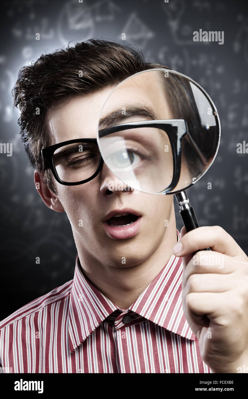 Young man scientist looking in magnifying glass Stock Photo - Alamy