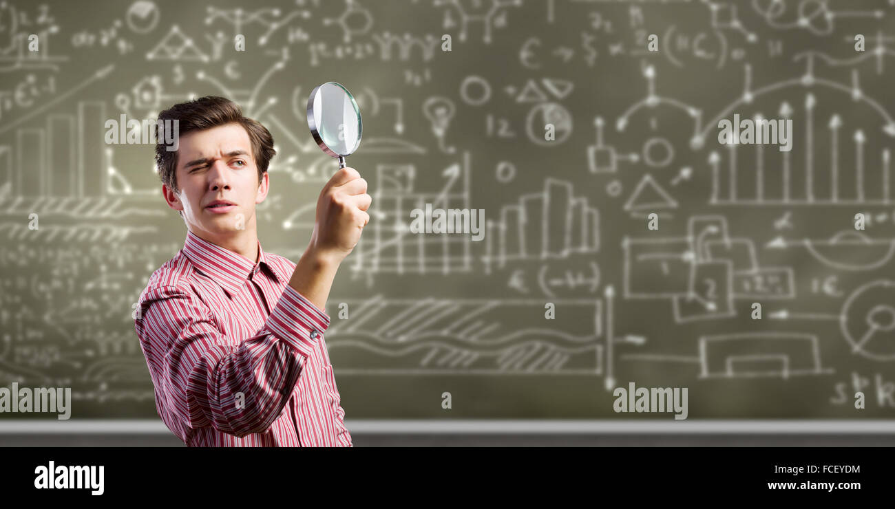 Young man scientist looking in magnifying glass Stock Photo - Alamy