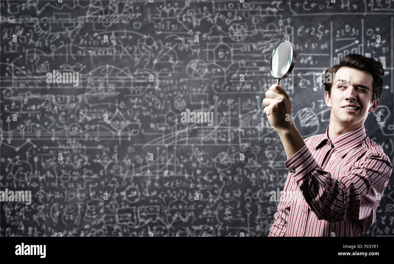 Young man scientist looking in magnifying glass Stock Photo - Alamy