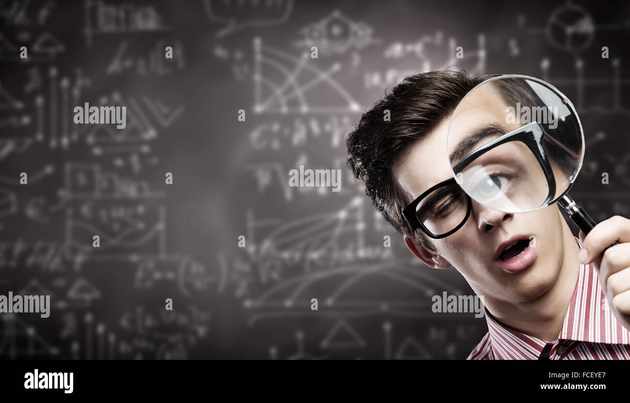 Young man scientist looking in magnifying glass Stock Photo - Alamy