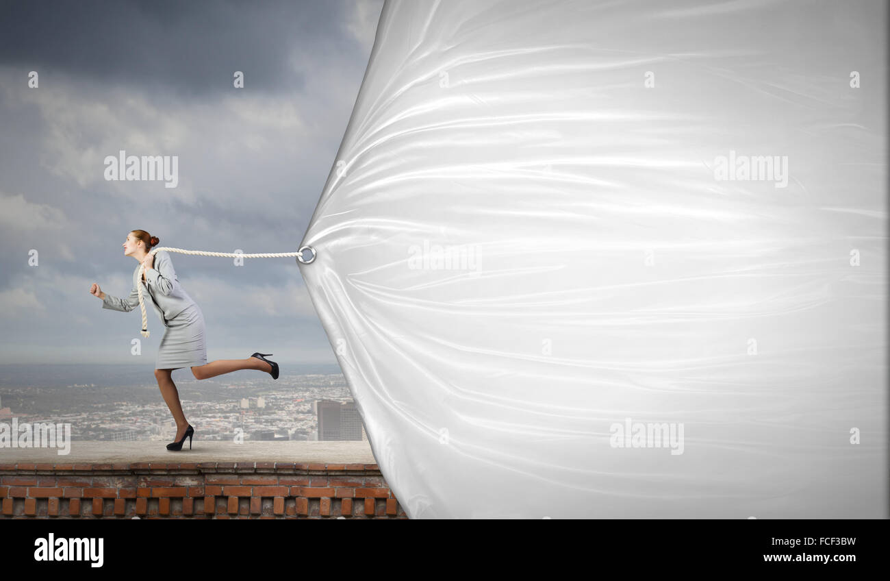 Young businesswoman running and pulling white blank banner Stock Photo ...
