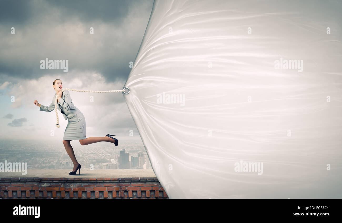 Young businesswoman running and pulling white blank banner Stock Photo ...