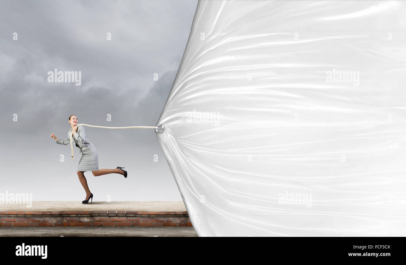 Young businesswoman running and pulling white blank banner Stock Photo ...
