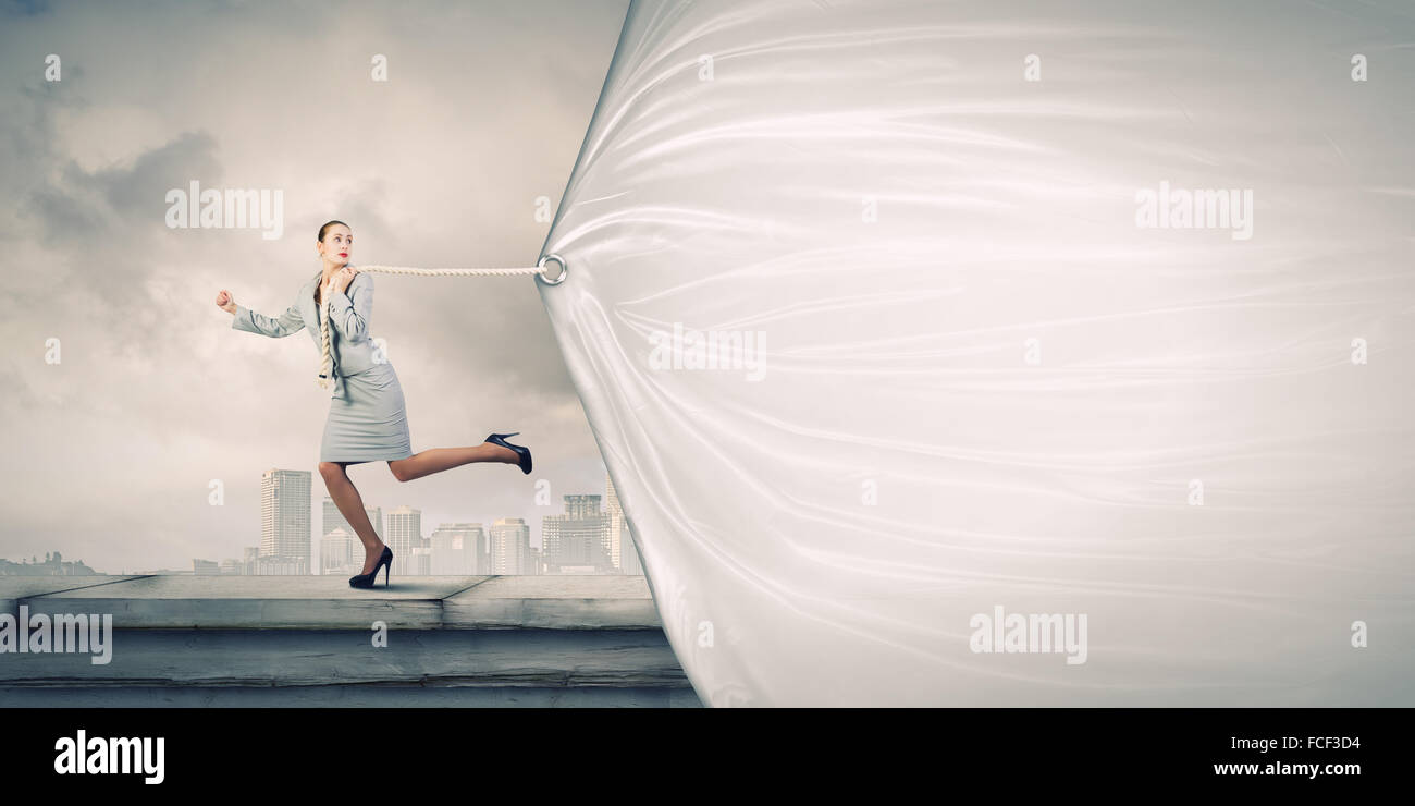 Young businesswoman running and pulling white blank banner Stock Photo ...