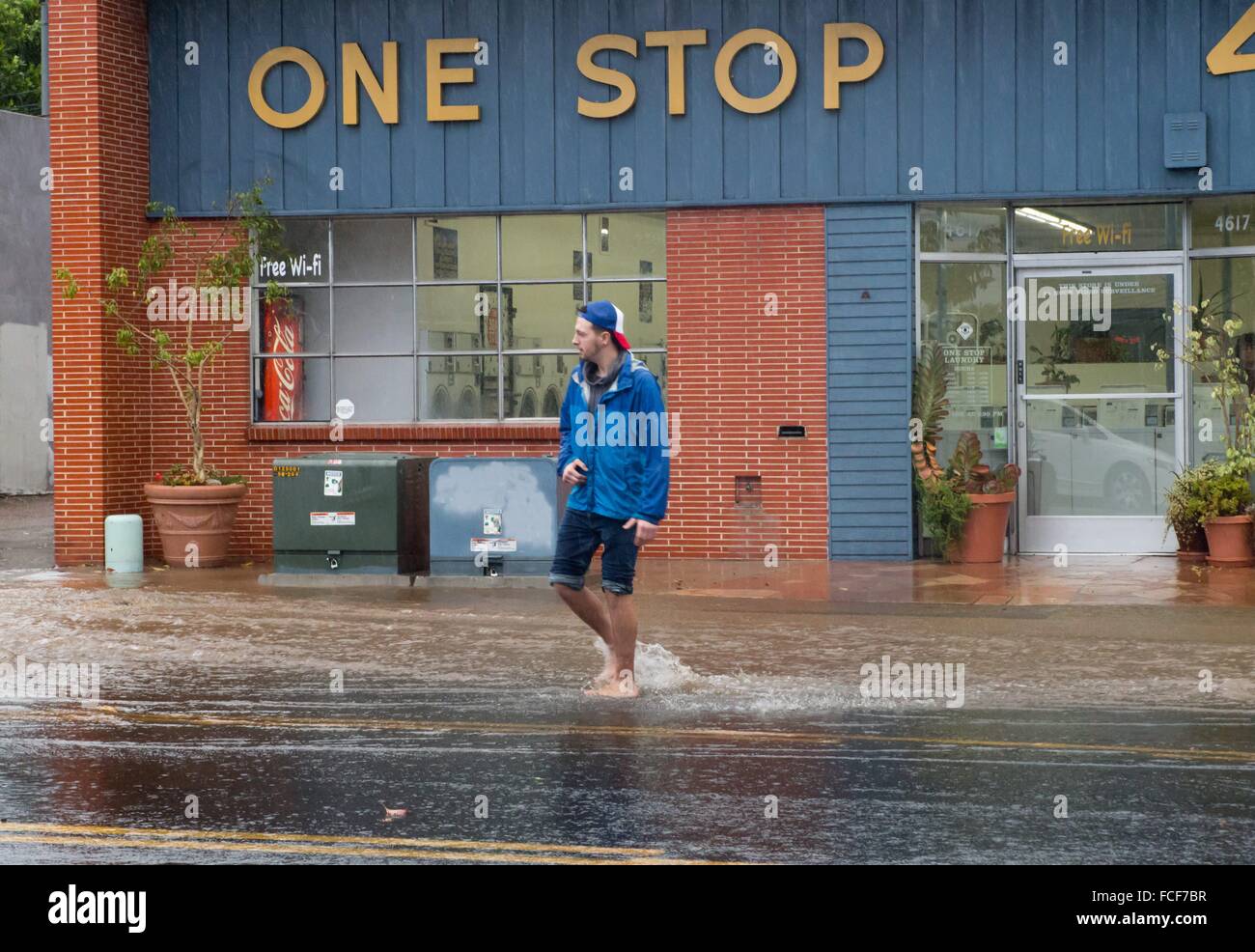 Man without shoes standing on a flooded sidewalk in Pacific Beach next ...