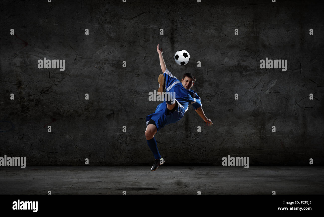 Football player kicking ball against dark background Stock Photo - Alamy