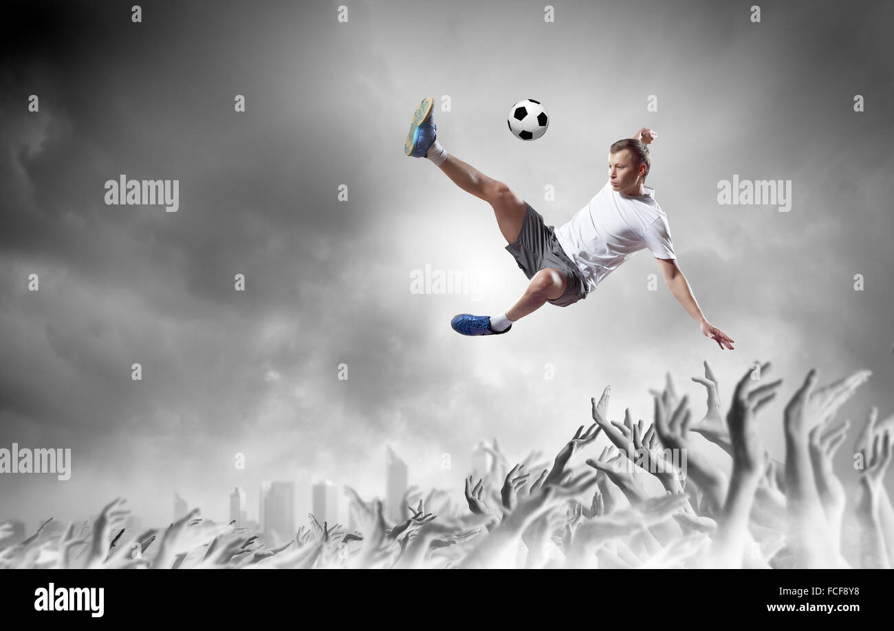 Football player in jump kicking the ball supported by fans Stock Photo ...
