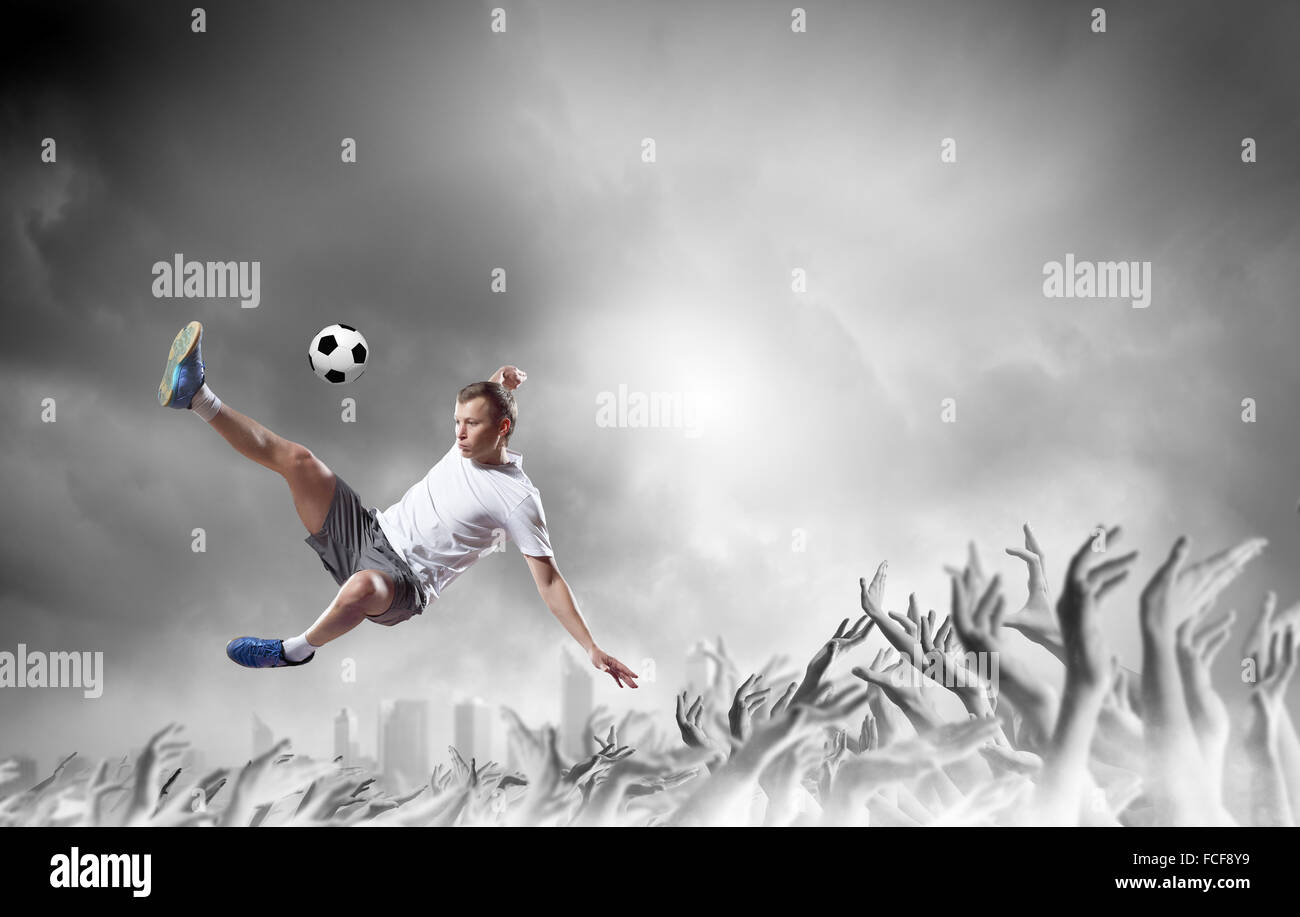 Football player in jump kicking the ball supported by fans Stock Photo ...