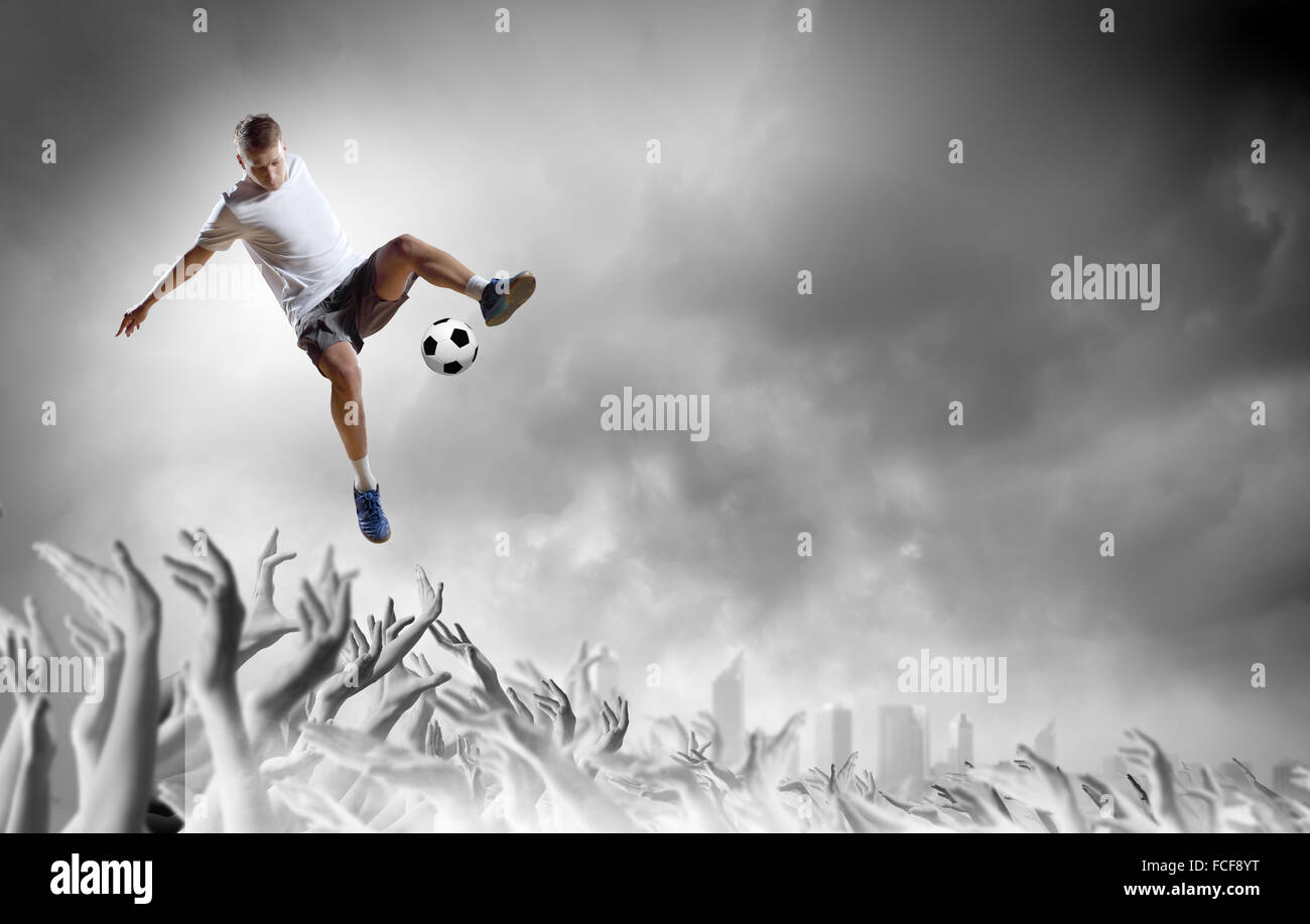 Football player in jump kicking the ball supported by fans Stock Photo ...