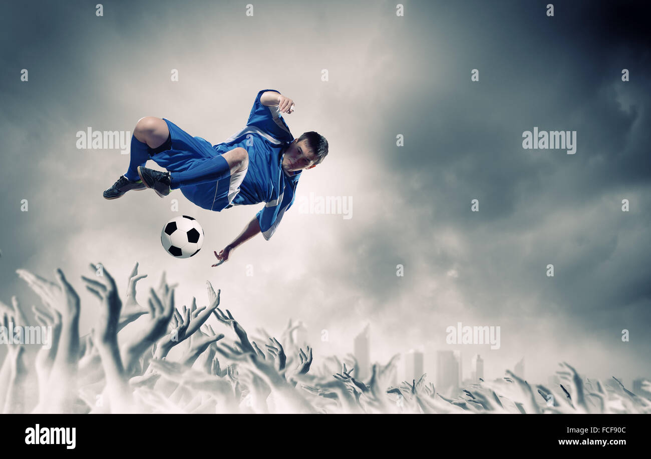 Football player in jump kicking the ball supported by fans Stock Photo ...
