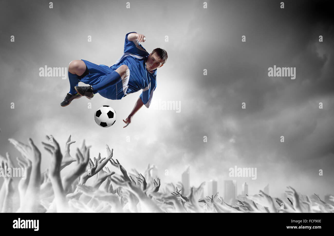Football player in jump kicking the ball supported by fans Stock Photo ...