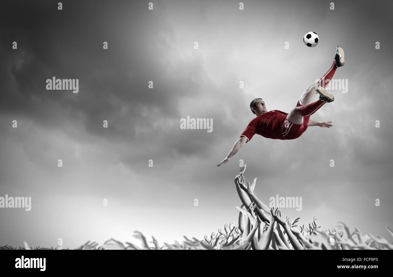 Football player in jump kicking the ball supported by fans Stock Photo ...