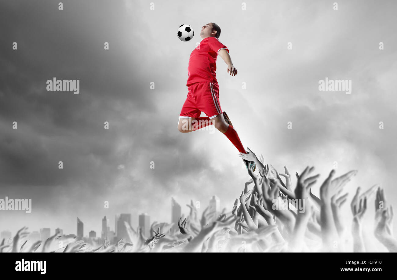 Football player in jump kicking the ball supported by fans Stock Photo ...