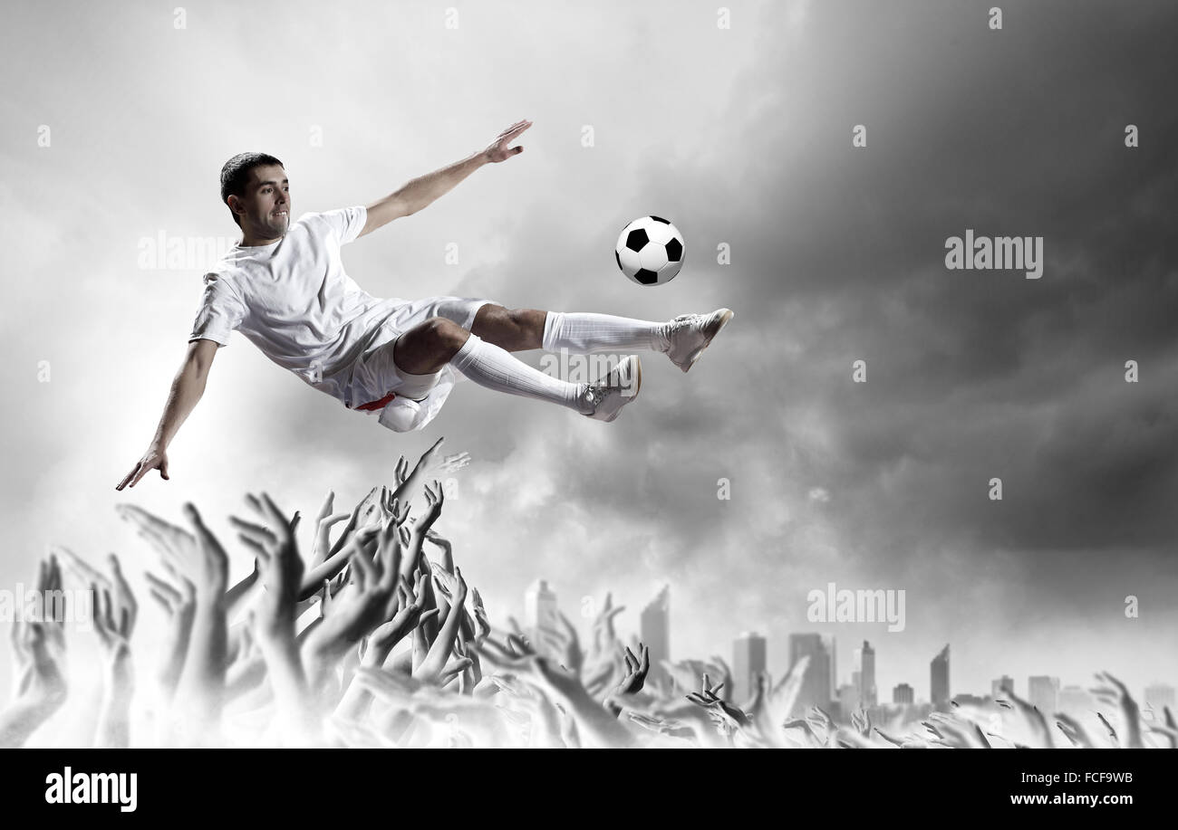 Football player in jump kicking the ball supported by fans Stock Photo ...