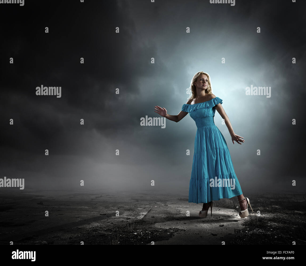 Anxious young woman in blue dress looking back worried Stock Photo - Alamy