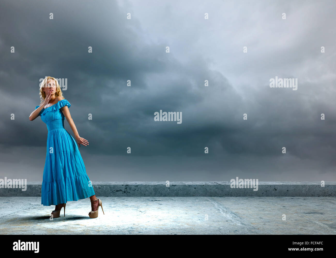 Anxious young woman in blue dress looking back worried Stock Photo - Alamy