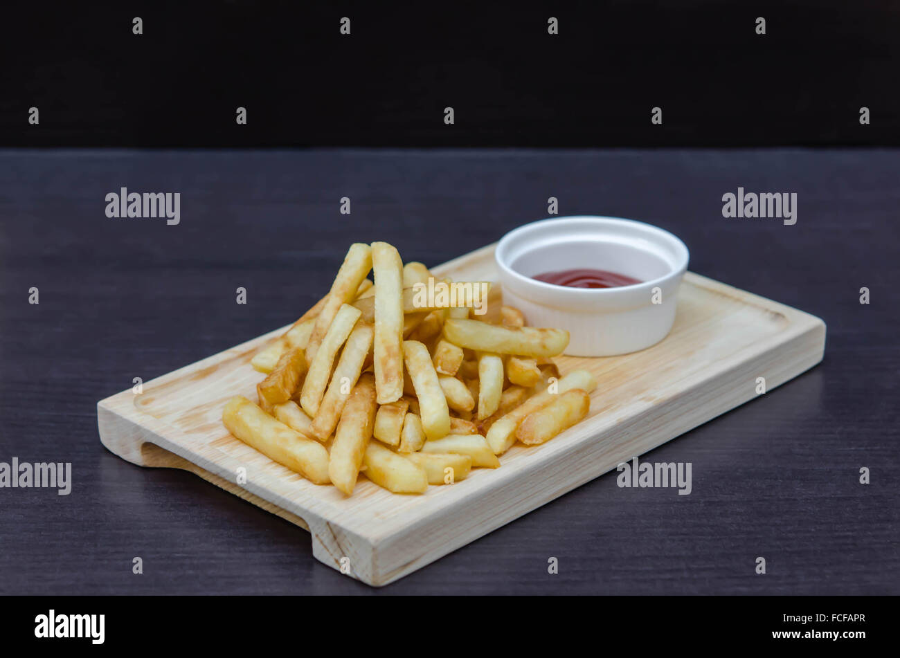 Traditional French fries on wooden plate with tomato sauce Stock Photo ...