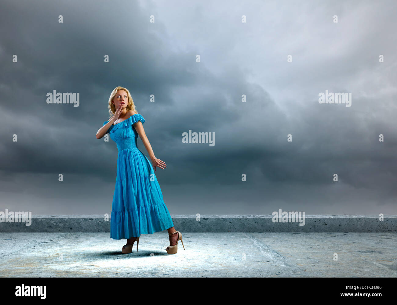 Anxious young woman in blue dress looking back worried Stock Photo - Alamy