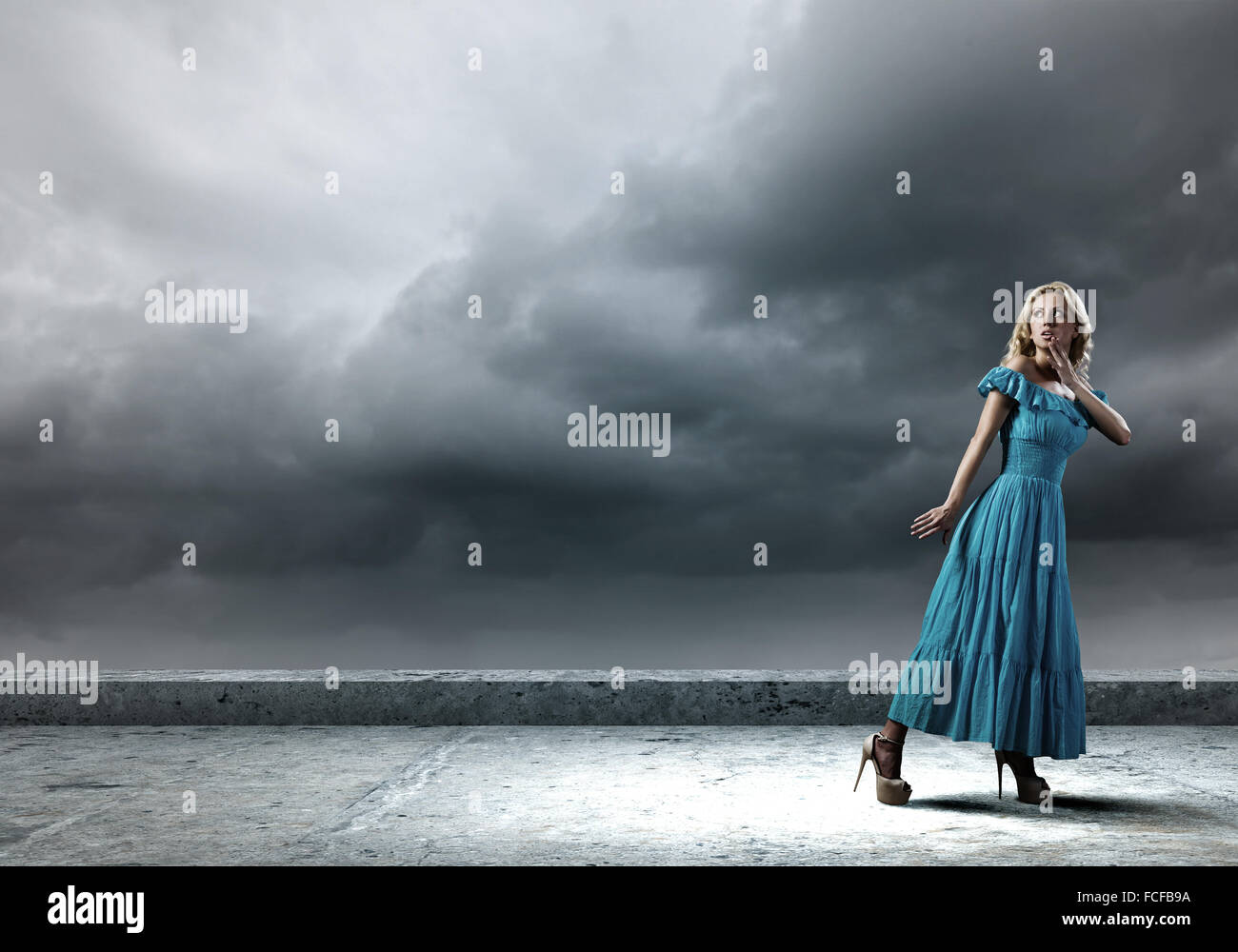 Anxious young woman in blue dress looking back worried Stock Photo - Alamy