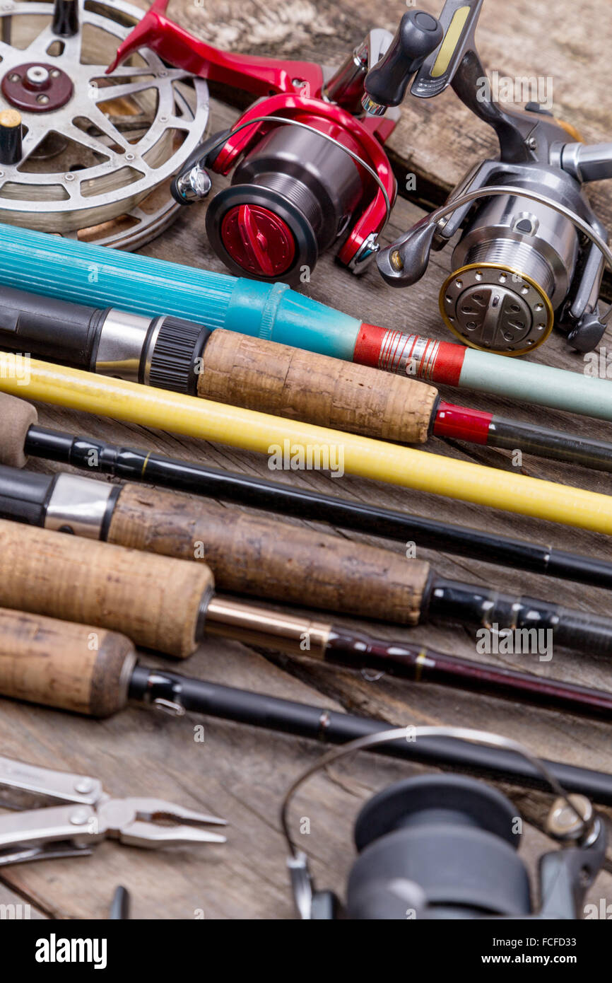 different fishing rods and reels on wooden boards background. creative ...