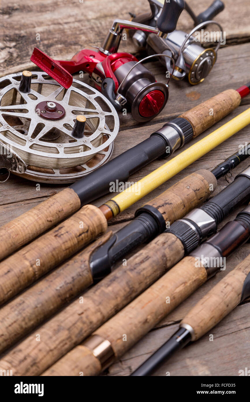 different fishing rods and reels on wooden boards background. creative ...