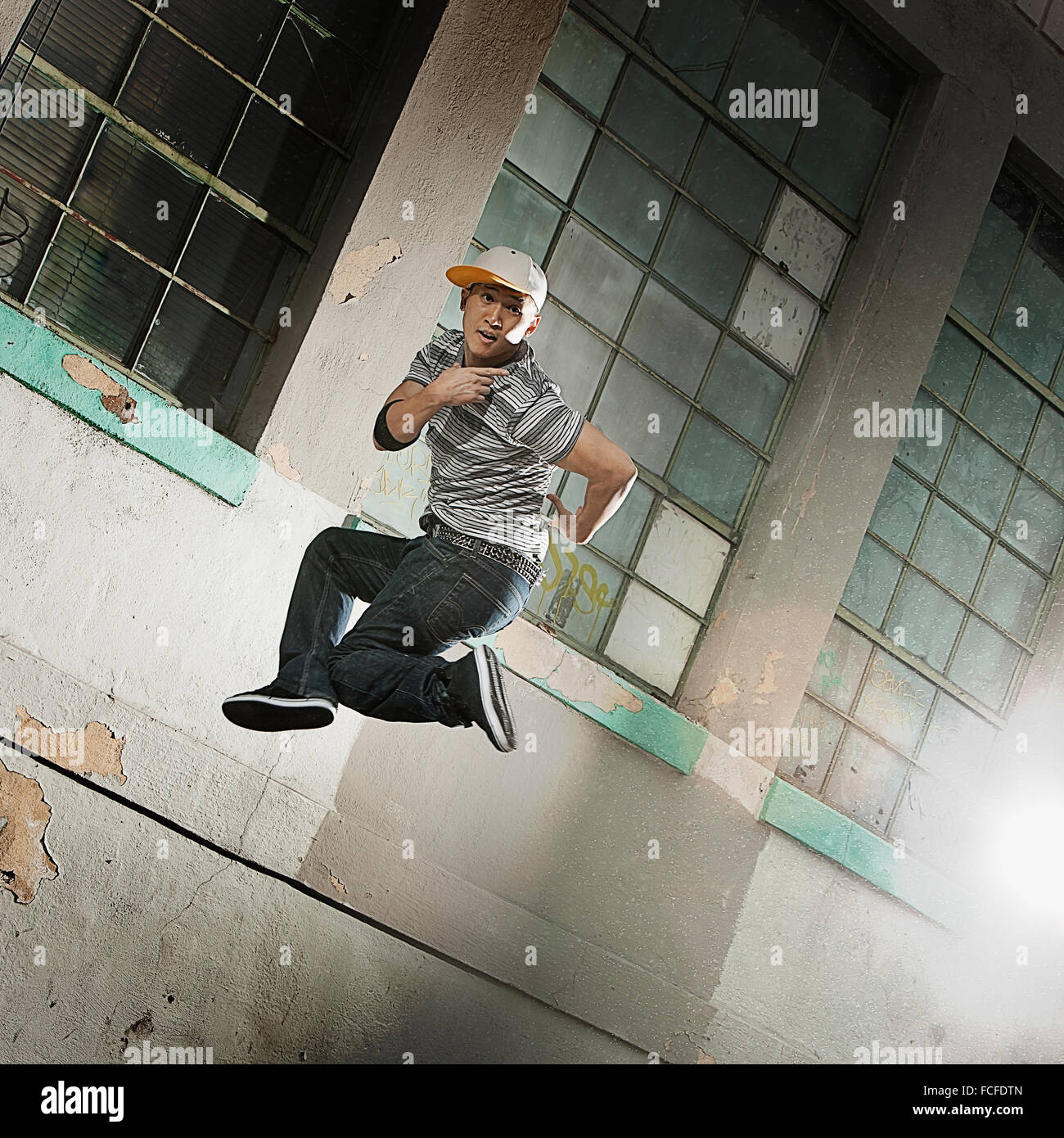 A young man breakdancing on a city sidewalk leaping in the air and ...