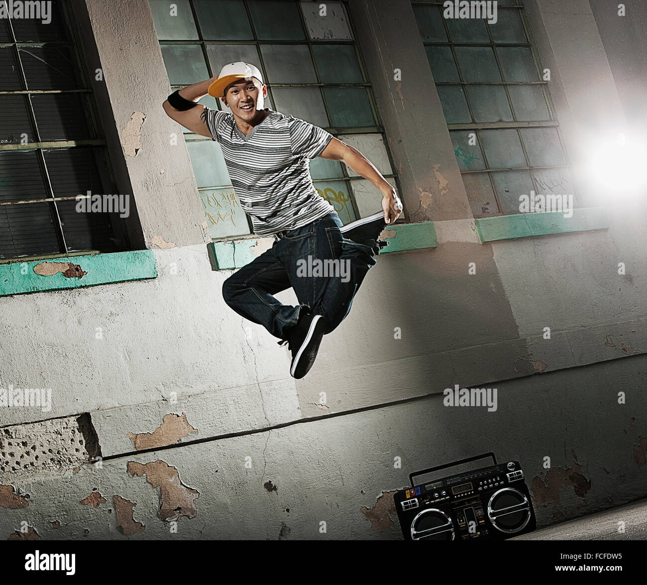A young man breakdancing on a city sidewalk leaping in the air and ...
