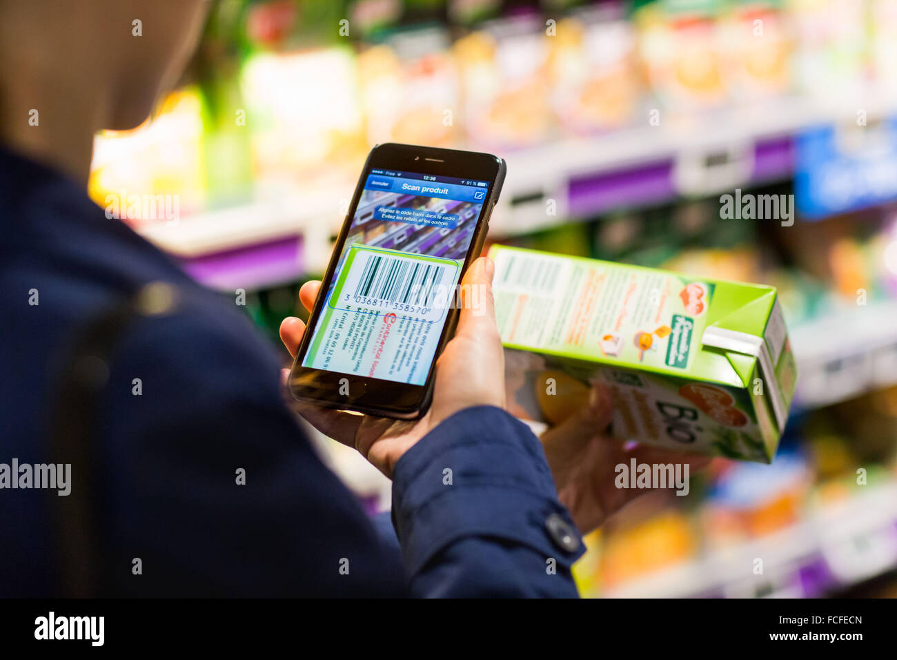 Woman using a smartphone in supermarket Stock Photo - Alamy