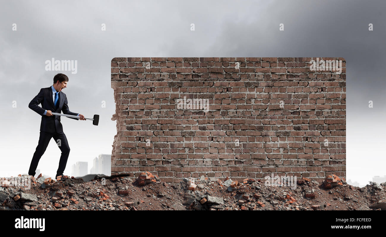 Young determined businessman breaking wall with hammer Stock Photo - Alamy