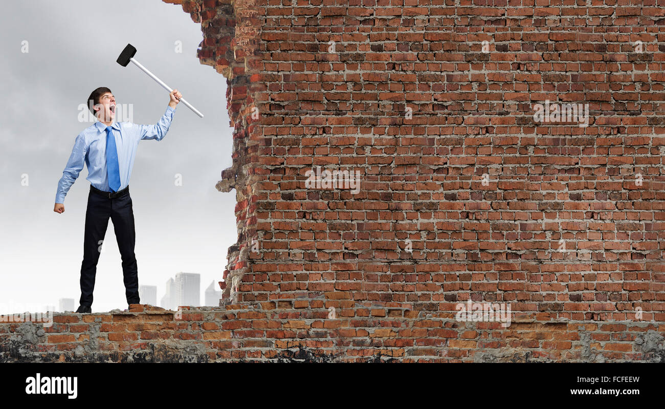 Young determined businessman breaking wall with hammer Stock Photo - Alamy