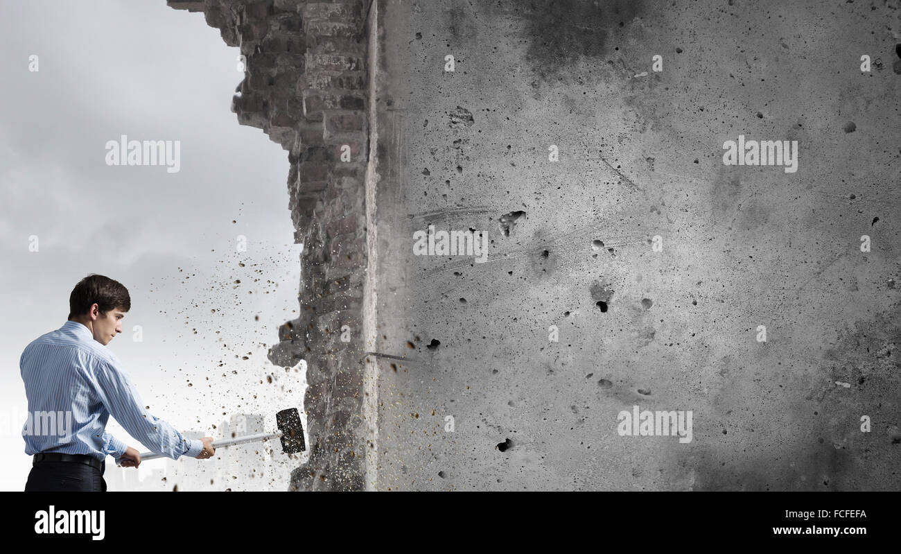 Young determined businessman breaking wall with hammer Stock Photo - Alamy
