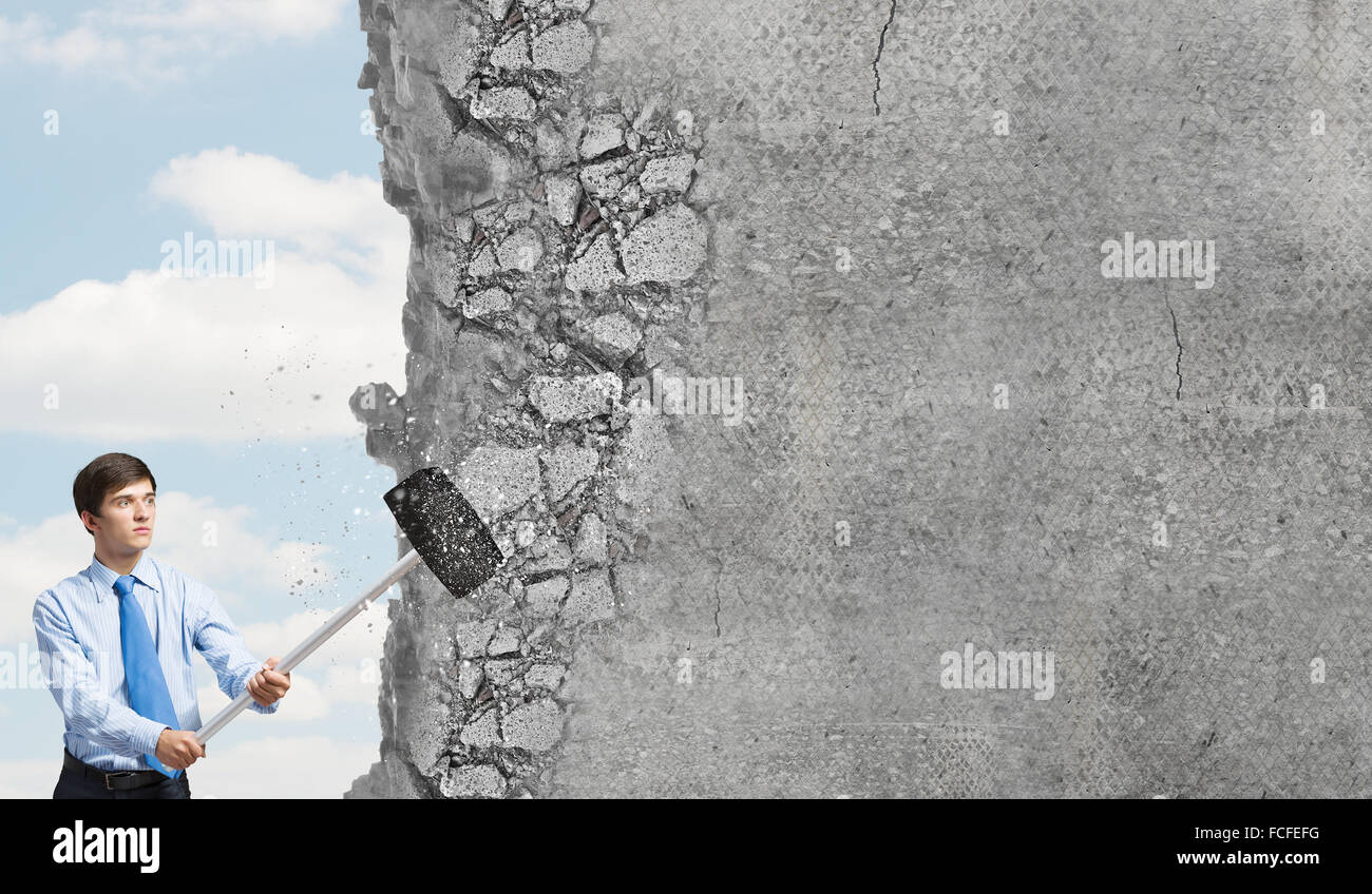 Young determined businessman breaking wall with hammer Stock Photo - Alamy