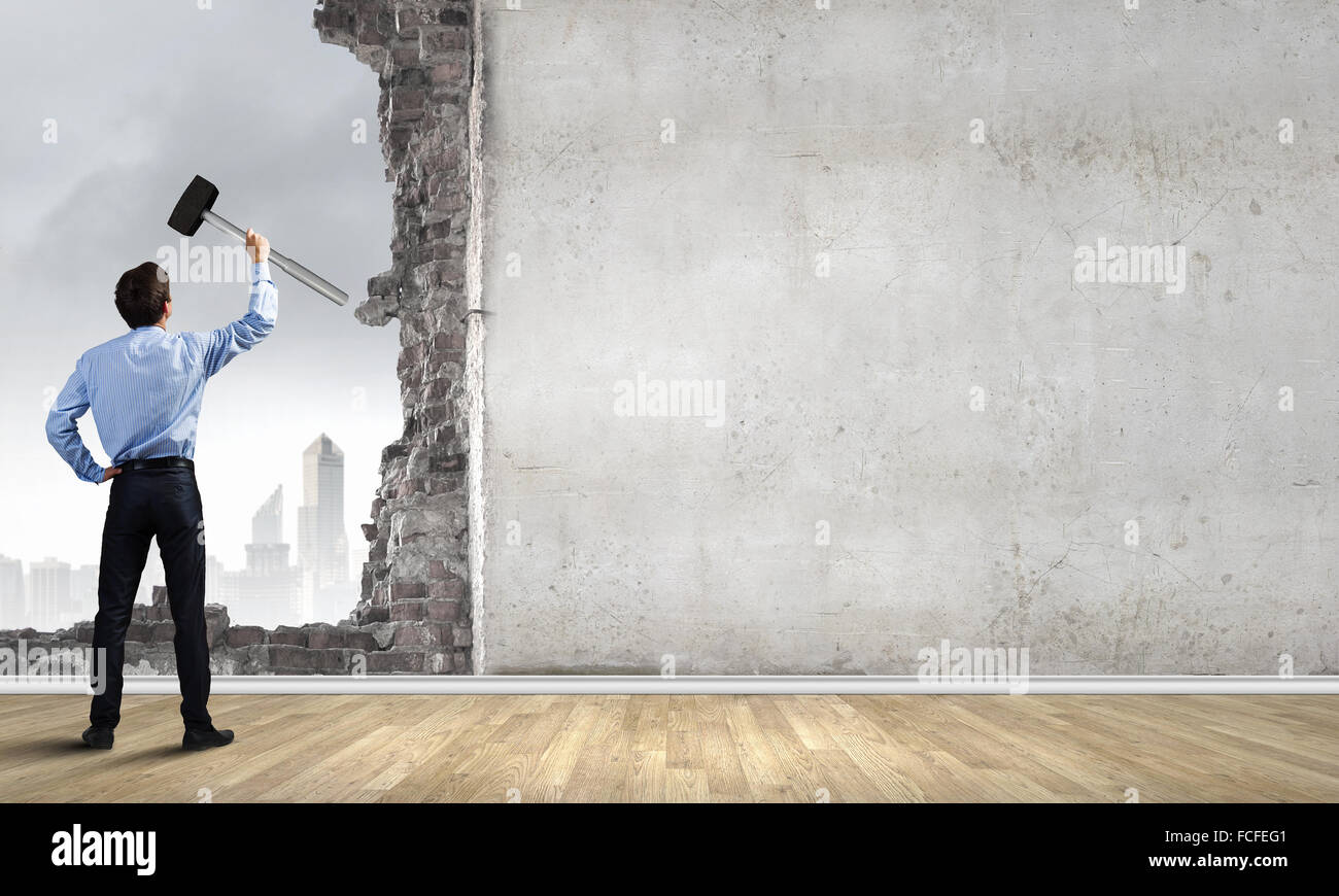 Young determined businessman breaking wall with hammer Stock Photo - Alamy