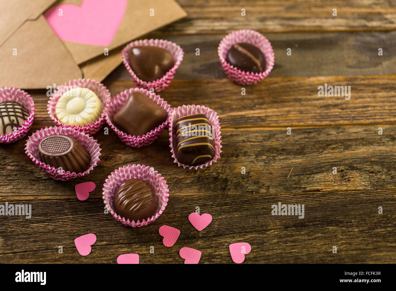 Assorted chocolates on rustic wood table Stock Photo - Alamy