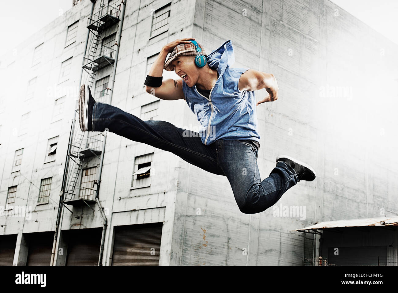 A young man doing a karate kick, one leg outstretched and one leg bent ...