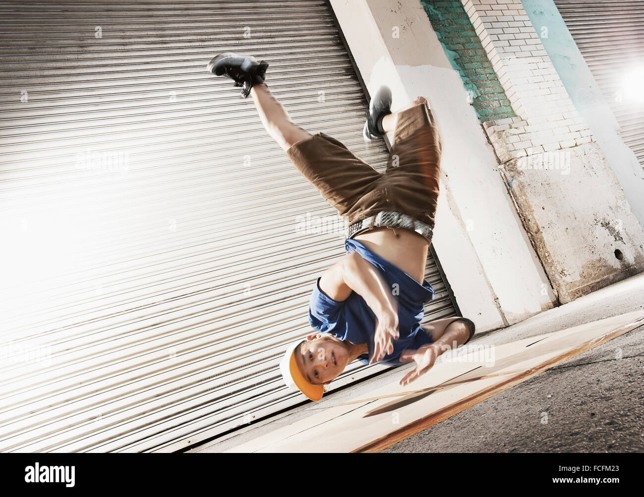 A young man upside down in mid air, break dancing doing a dive move on ...