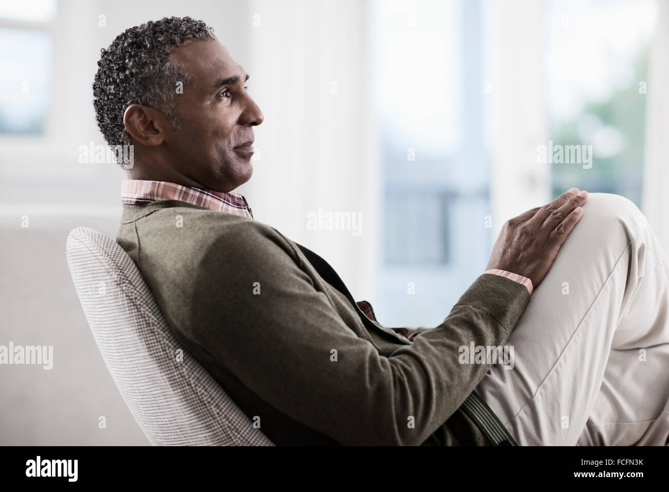A mature man seated in a chair leaning back relaxing Stock Photo - Alamy