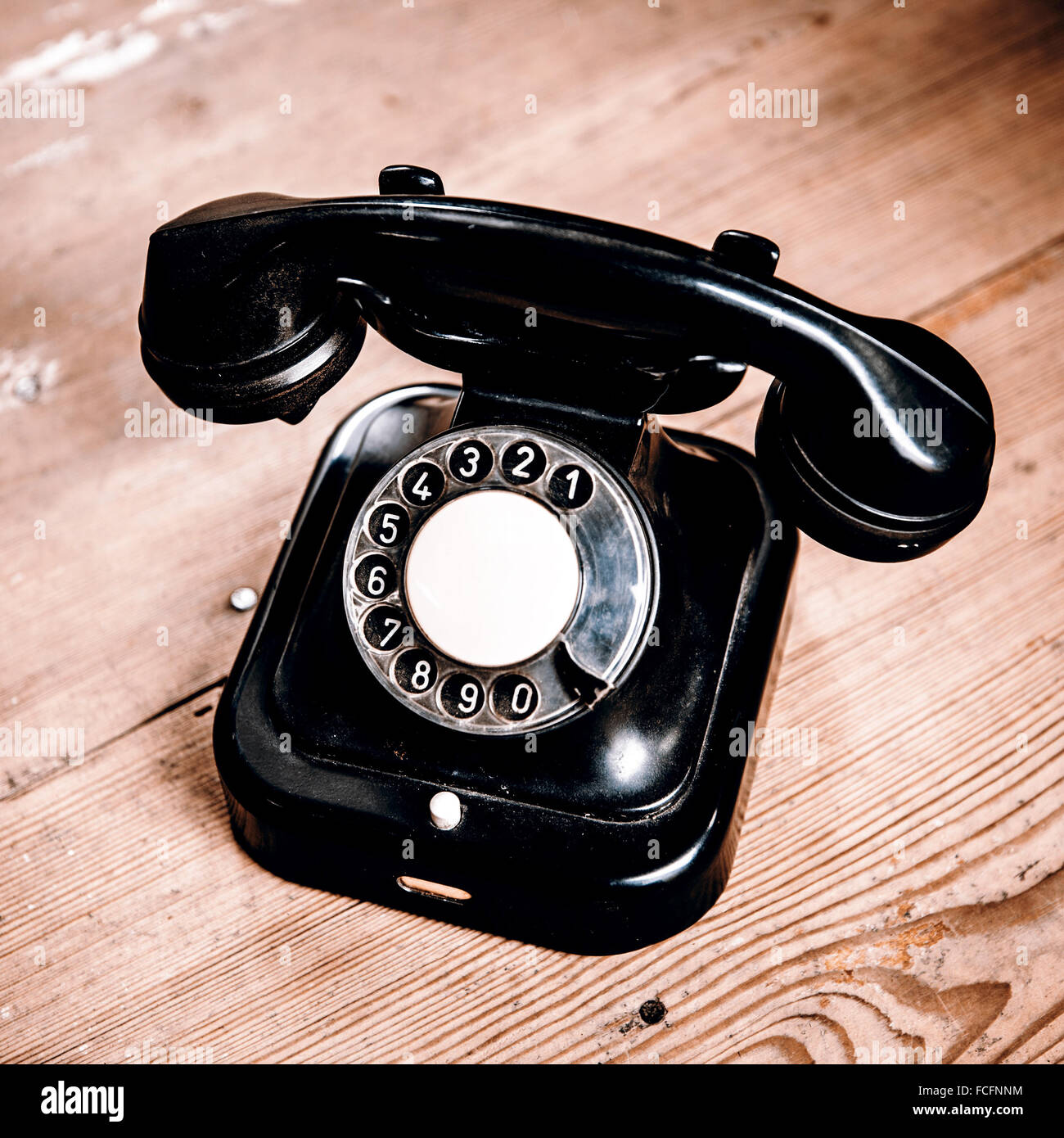 Old black phone with dust and scratches, isolated on wooden retro floor ...