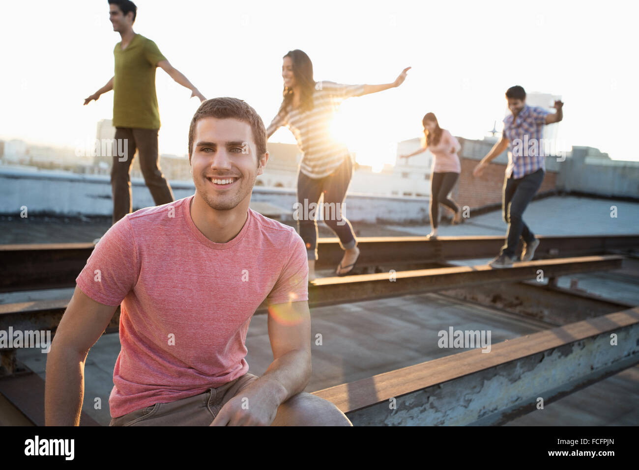A group of people on a rooftop in the city at dusk, balancing and ...