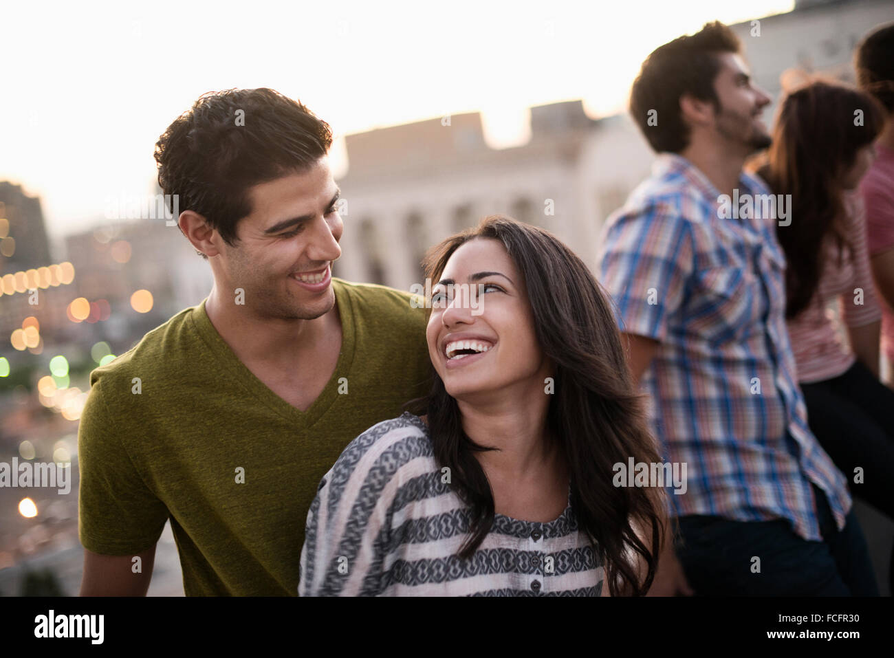 A small group of friends gathered on a rooftop terrace overlooking a ...