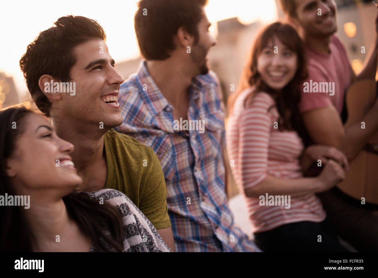 A small group of friends gathered on a rooftop terrace overlooking a ...