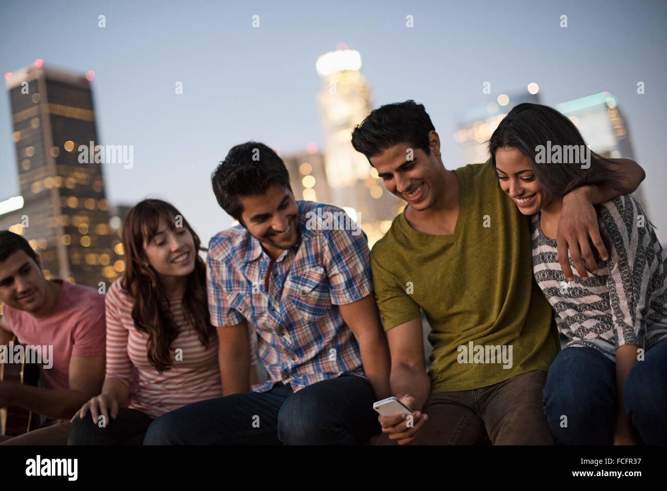 A small group of friends gathered on a rooftop terrace overlooking a ...