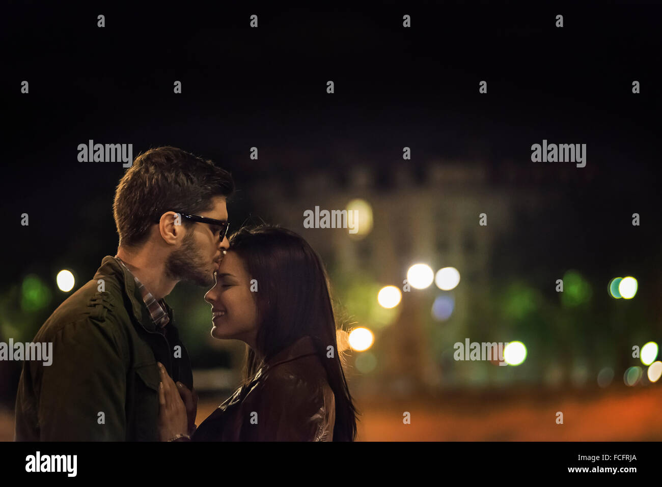 A couple kissing in a city at night Stock Photo - Alamy