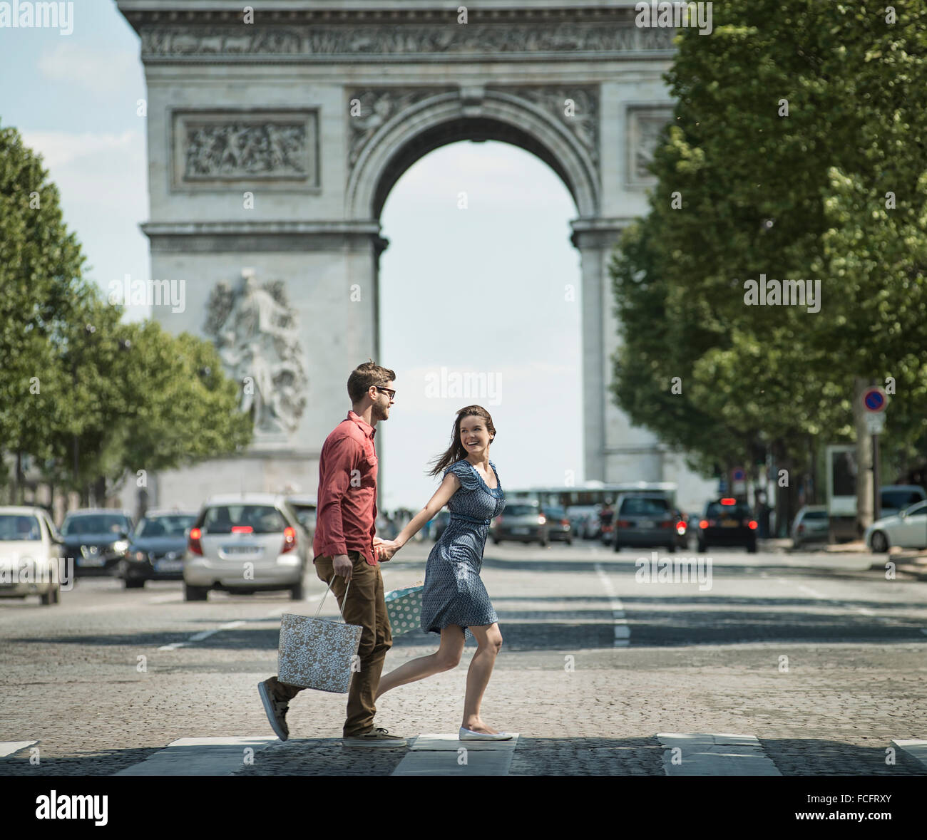 A couple hand in hand carrying shopping bags and crossing the road by a ...