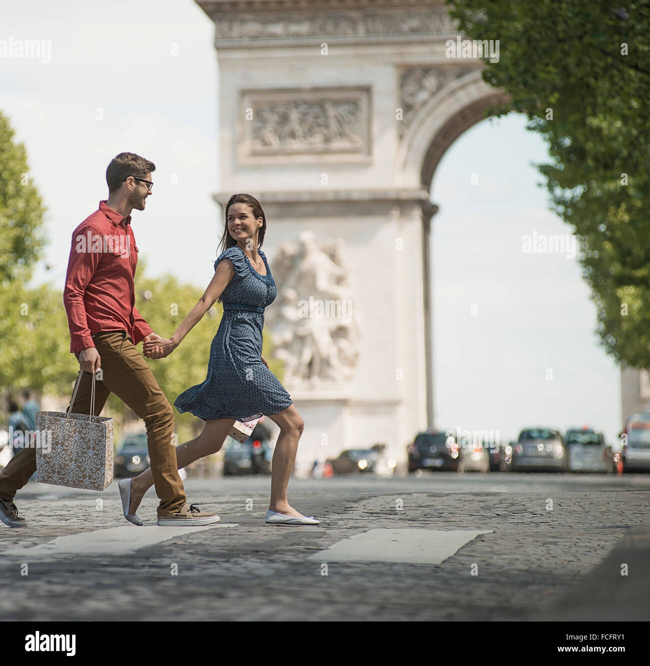 A couple hand in hand carrying shopping bags and crossing the road ...