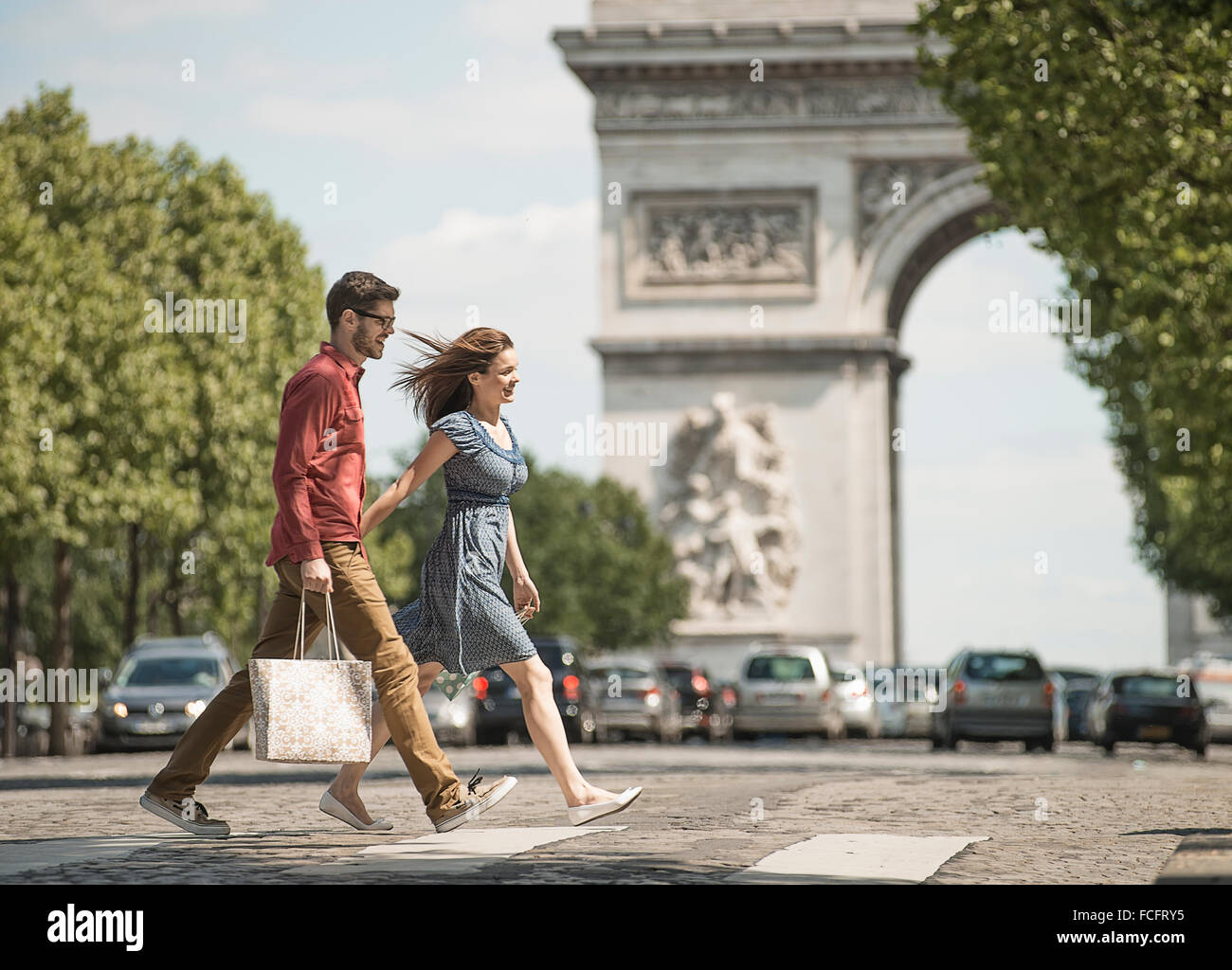 A couple hand in hand carrying shopping bags and crossing the road by a ...