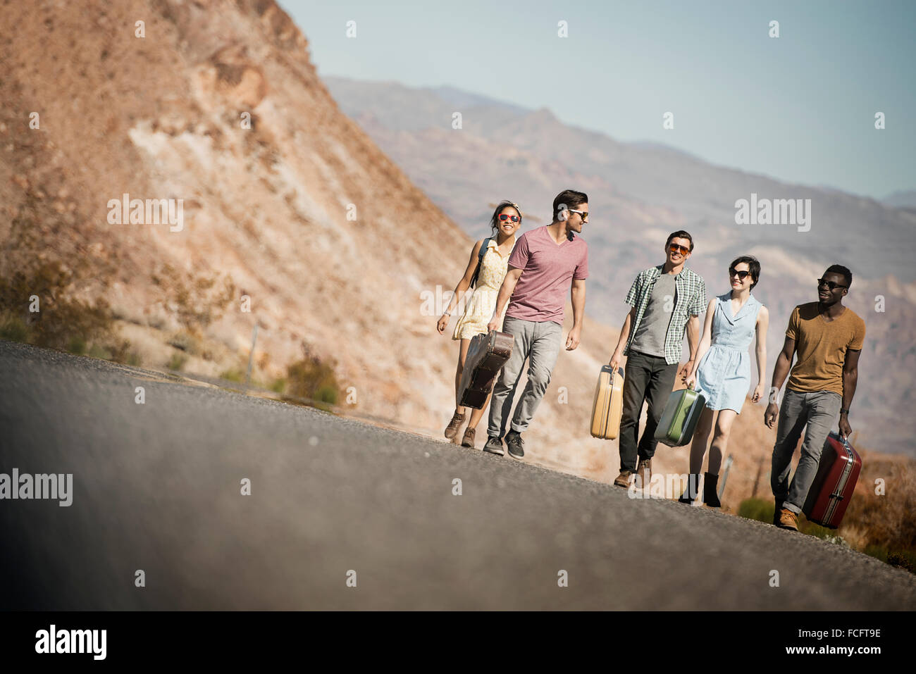 A group of people walking in a line in open desert country, carrying ...