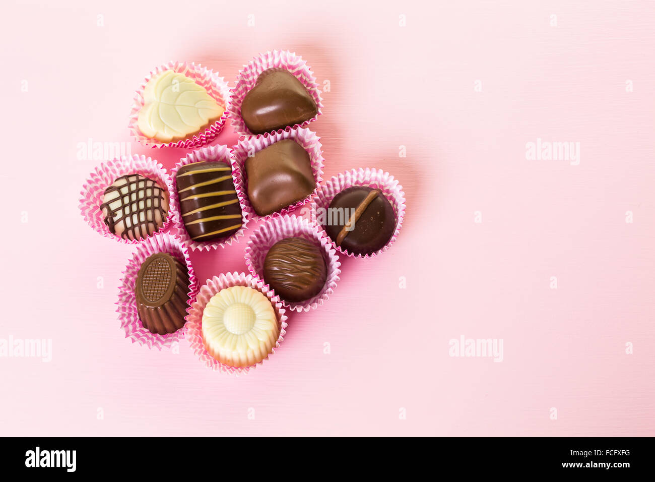 Assorted chocolates on pink background Stock Photo - Alamy